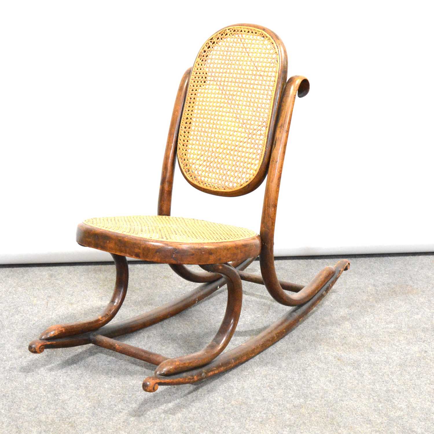 Lot 521 - A child's rattan cane rocking chair,